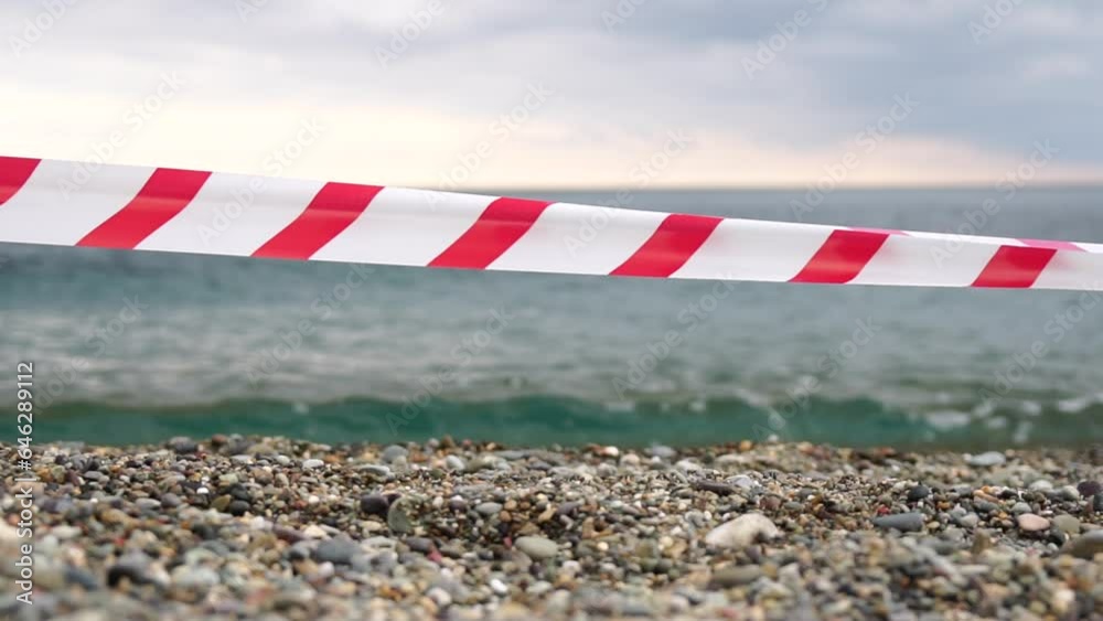 Red white warning tape barrier ribbon swinging in the wind across ...