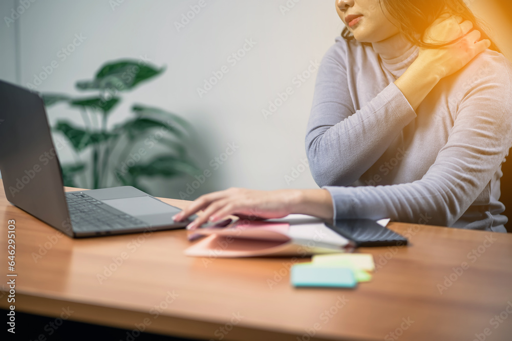 A Business woman sitting in office using laptop, work injury, neck and ...