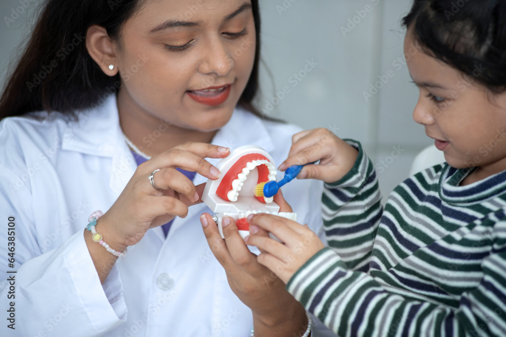 Dentist showing a jaw model to a little girl and suggest the correct ... Dentist showing a jaw model to a little girl and suggest the correct ...