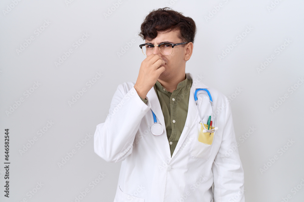 Young non binary man wearing doctor uniform and stethoscope smelling ...