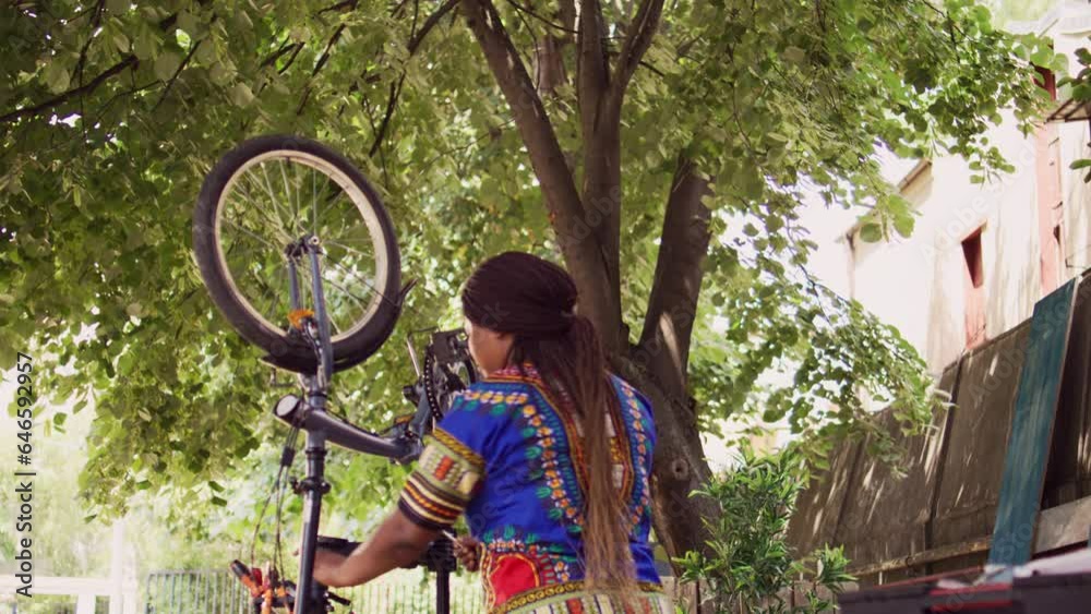 Healthy black woman mending her own bicycle using specialized equipment ...