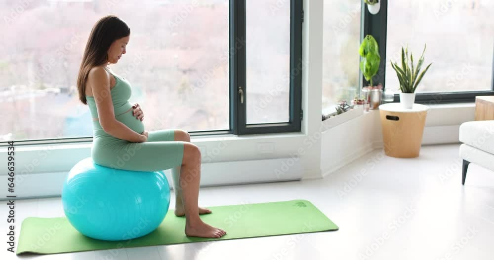 Pregnant woman sitting on exercise birth ball touching big belly baby ...