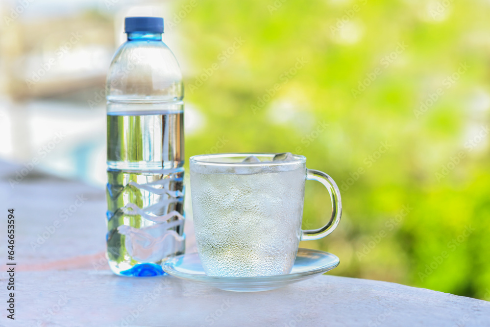 Glass of iced water and water bottle on white balcony rim with fresh ...