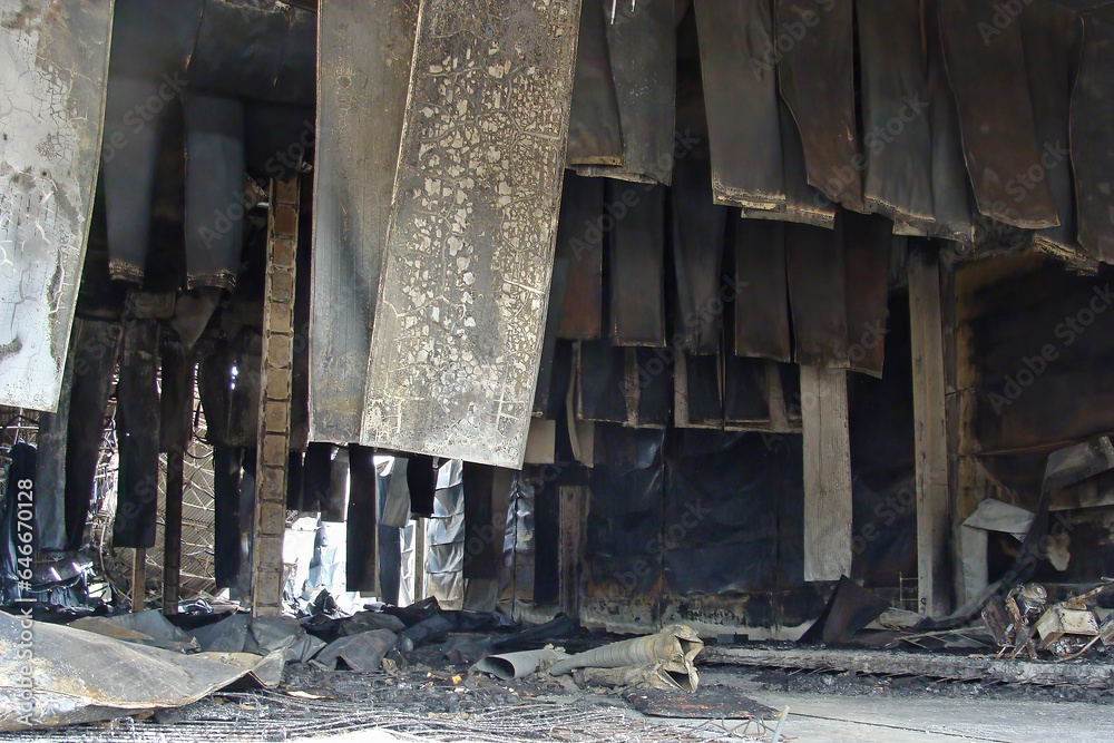 After a warehouse fire, black charred steel plates hang from the ...