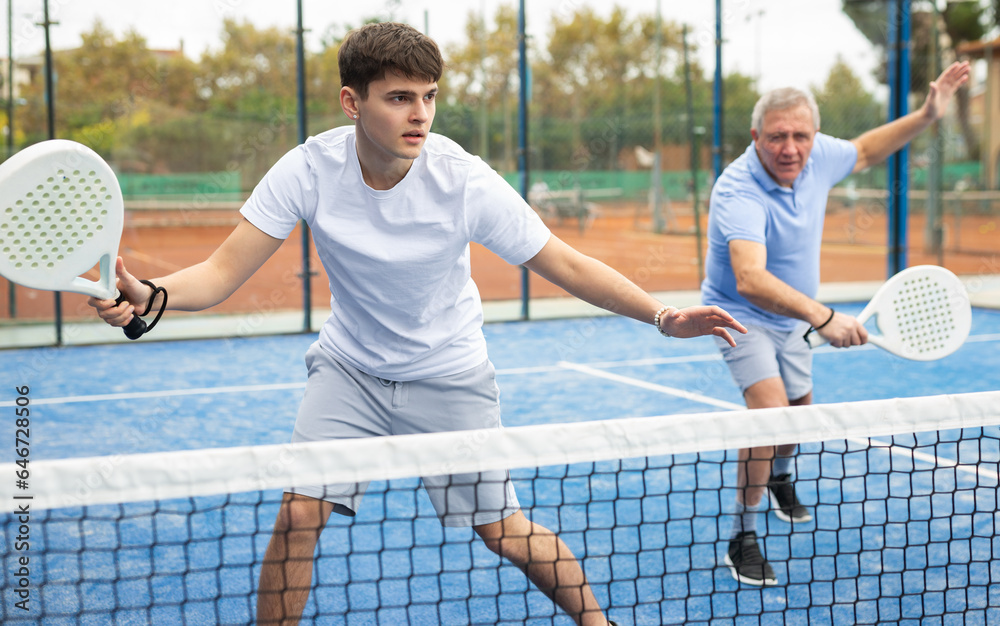 Portrait of emotional determined young guy playing padel tennis on open ...