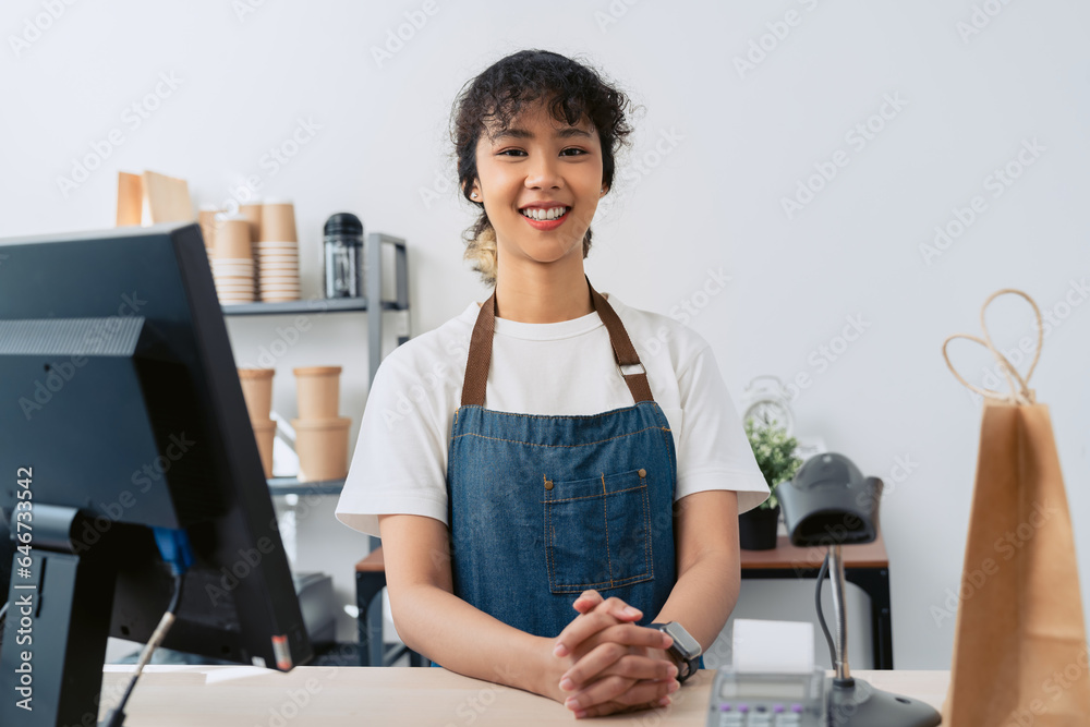 Happy young Asian woman cashier wears an apron and using pos terminal ...