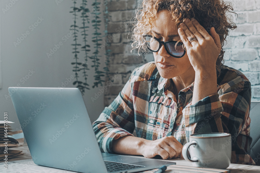 Exhausted woman with migraine headache sitting at the desk in front of ...