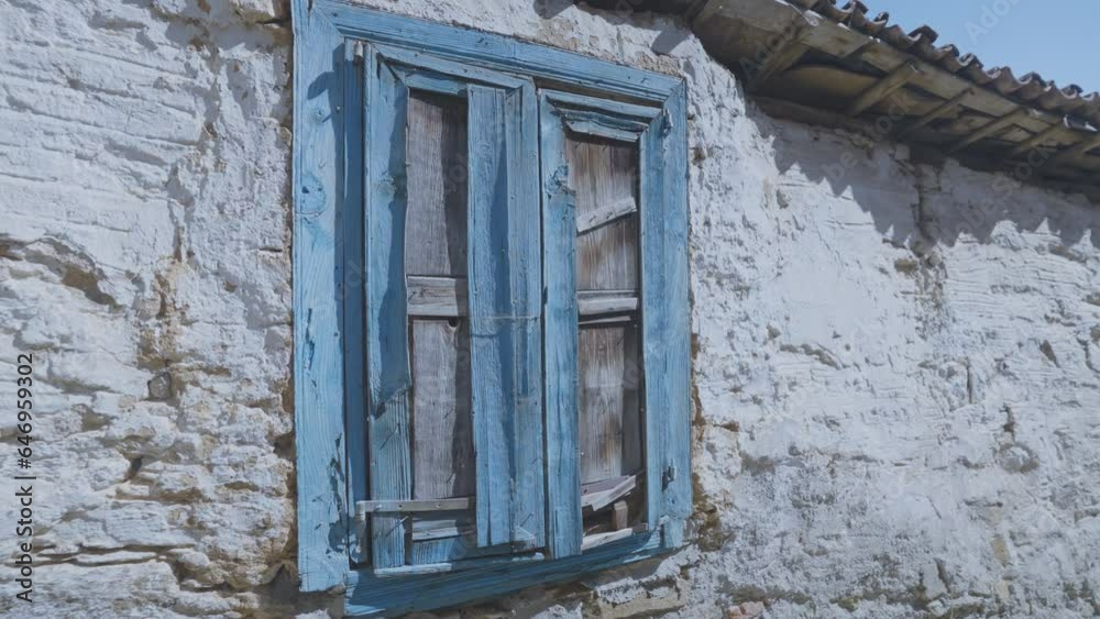 Old blue window covered with wooden planks in stone house lit by ...