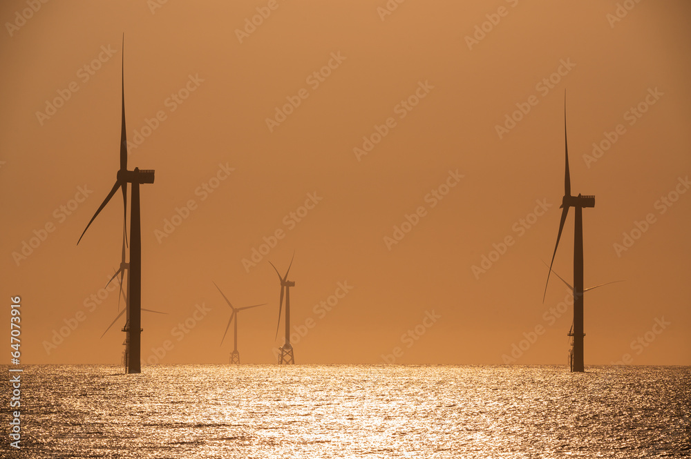 Fans of wind turbines spin over the sparkling sea. Dynamic clouds at ...