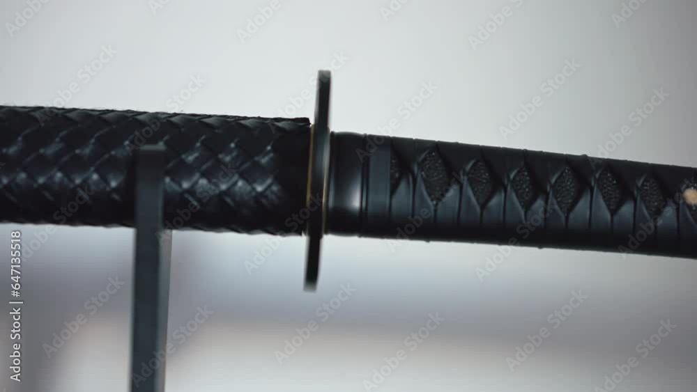 A masterfully crafted black katana with a scaly scabbard displayed on a ...