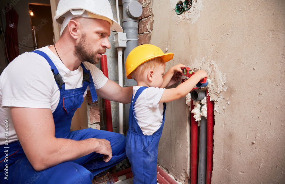 Father and son using spirit level tool while installing plumbing pipes ...