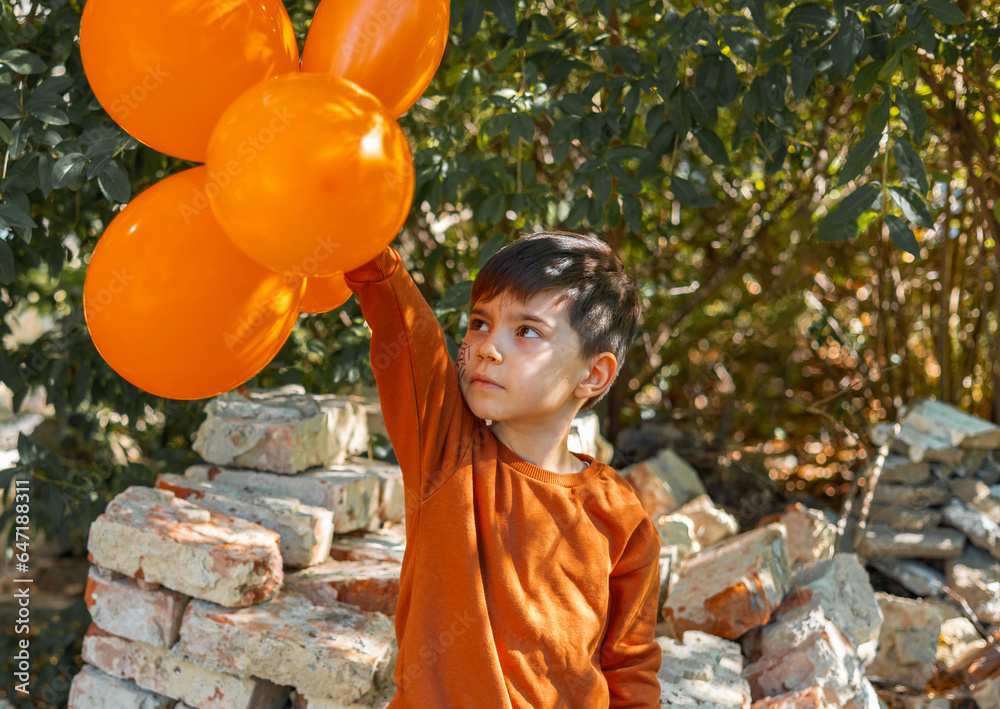 boy kid with orange balloons and spider web drawn on cheek playing ...