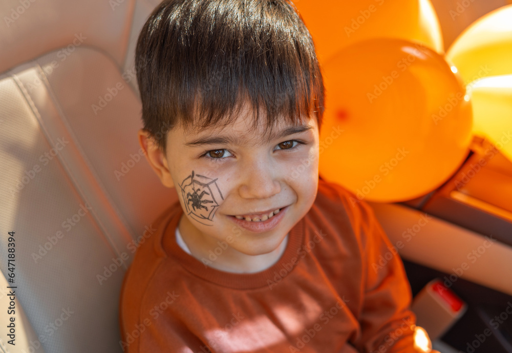 kid boy with orange balloons and spider web on face in car, with head ...