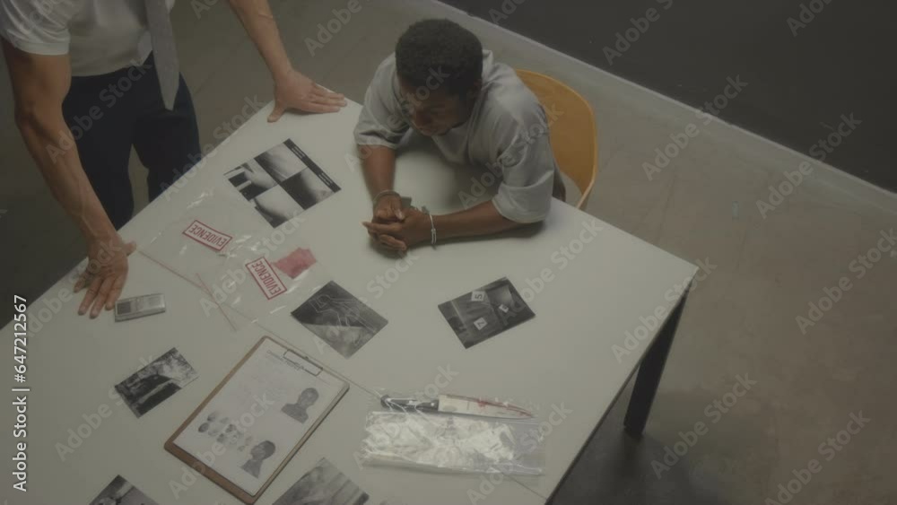 High angle shot of arrested Black man looking at physical evidence in ...