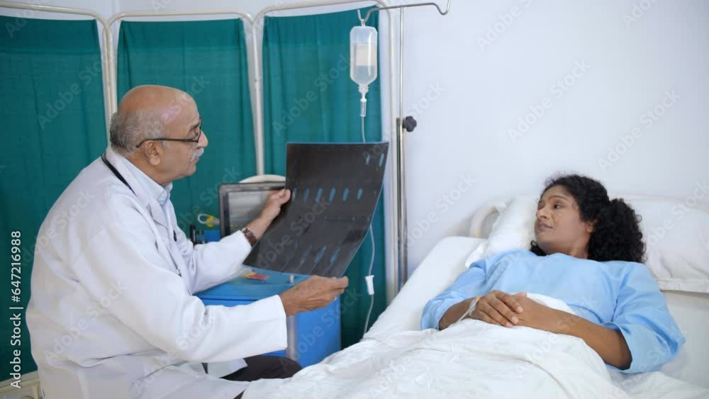 Indian old male doctor checking X-ray or MRI report for his female ...