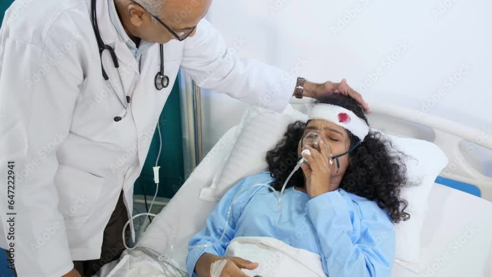 A senior Indian doctor puts an oxygen mask on his female patient ...