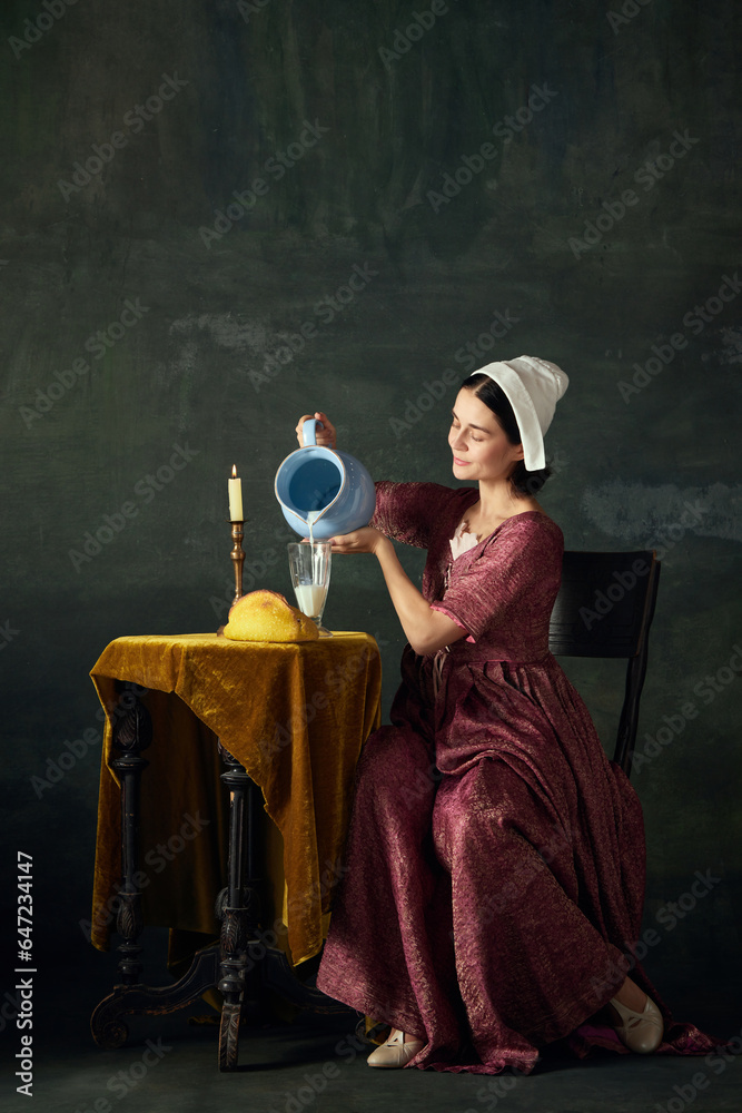 Beautiful woman, medieval maid in historical attire pouring milk ...
