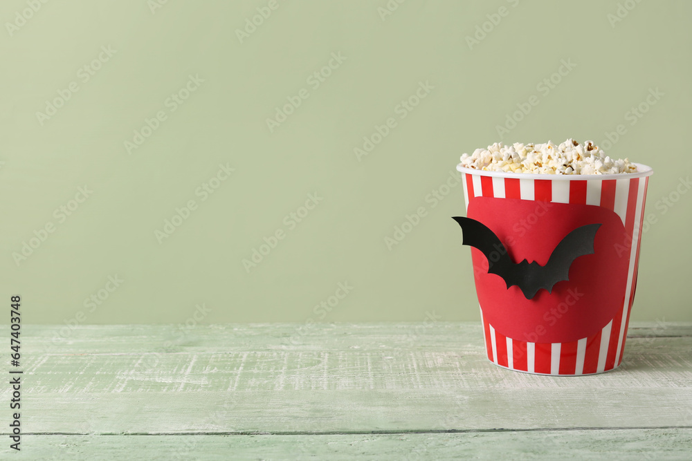 Popcorn bucket with Halloween bats on wooden table against green ...