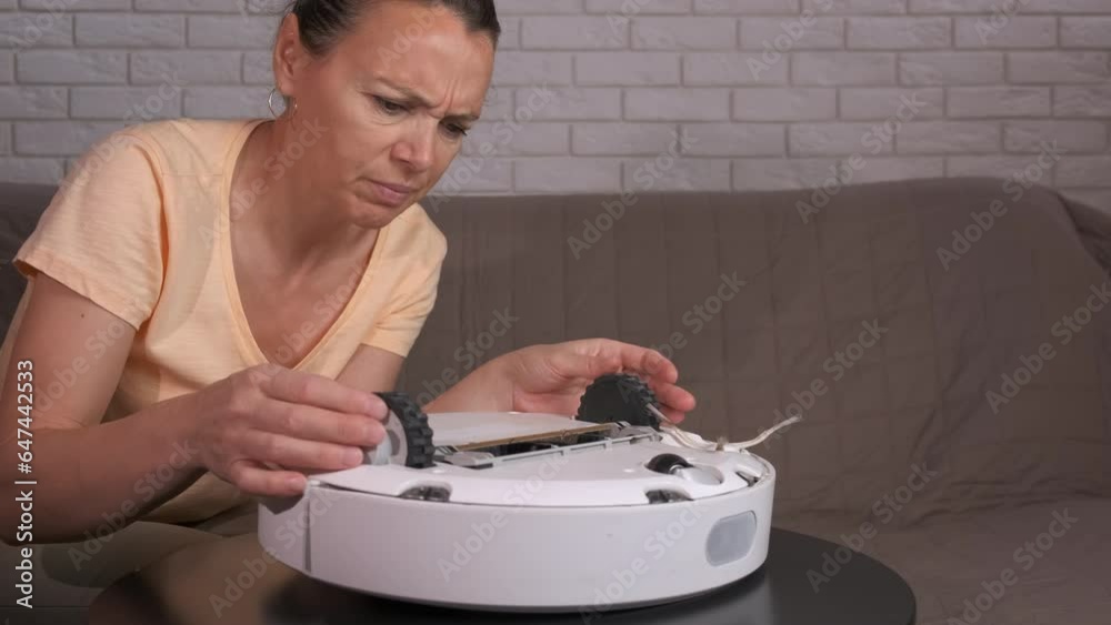 Replacement of parts of robot vacuum cleaner. A woman try to replace ...