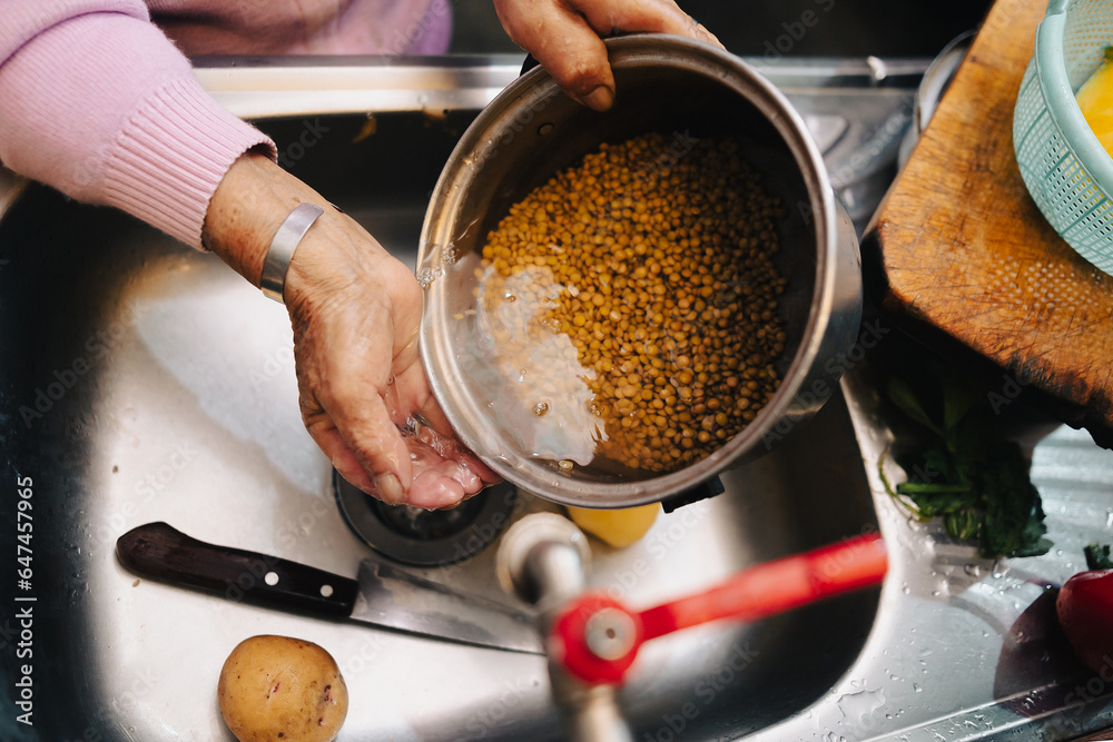 Elderly hands washing lentils in the kitchen. Stock Photo | Adobe Stock