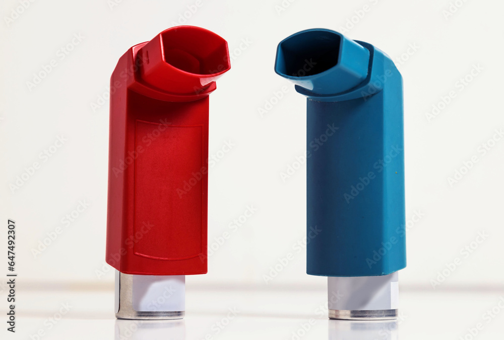 Two asthma inhalers facing each other, in red and blue, isolated on a ...
