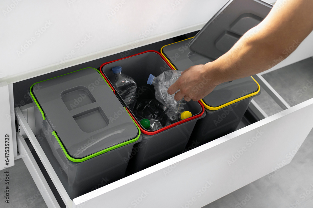 A young man sorts garbage in containers in the kitchen in slow motion ...