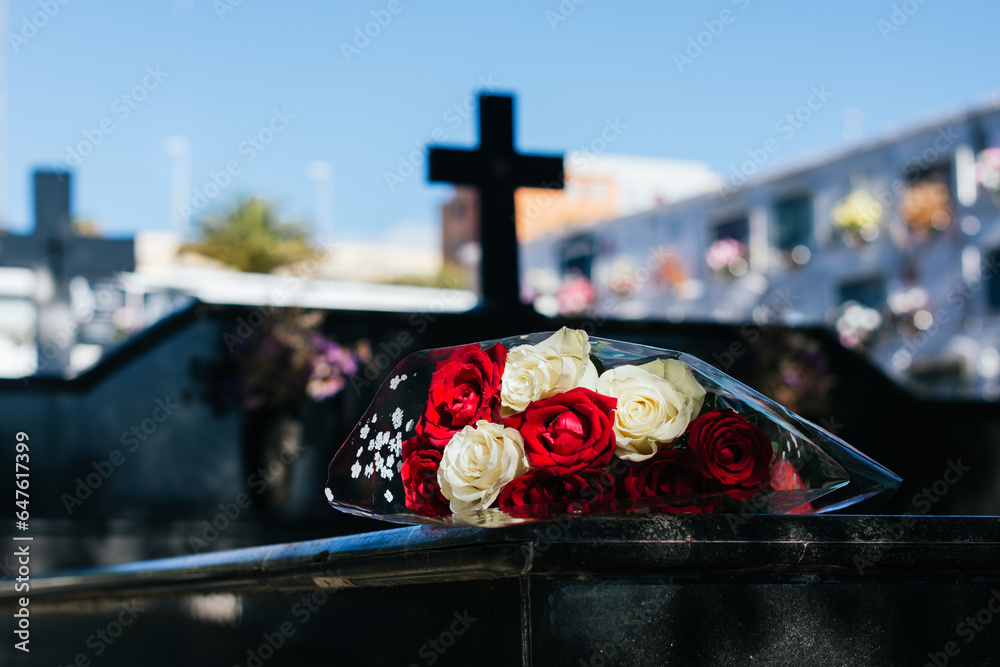 White and red roses on black granite tombstone outdoors. Funeral ...
