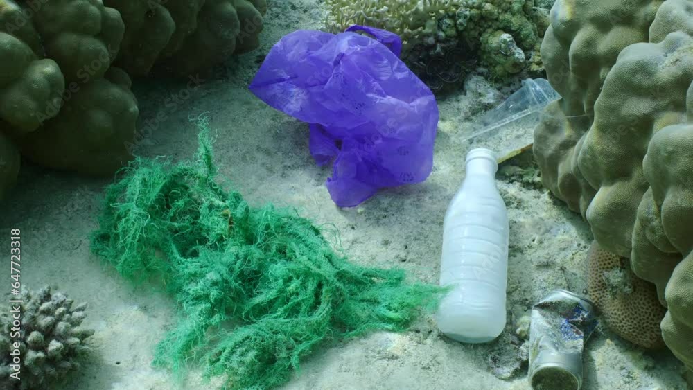Top view of plastic pollution on beautiful shallow coral reef, Close up ...