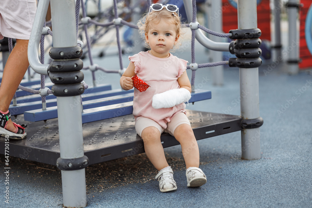Adorable toddler with a broken arm of a child in a cast sitting on the ...
