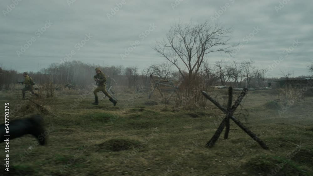 Tracking shot of men wearing Soviet Red Army uniforms holding firearms ...