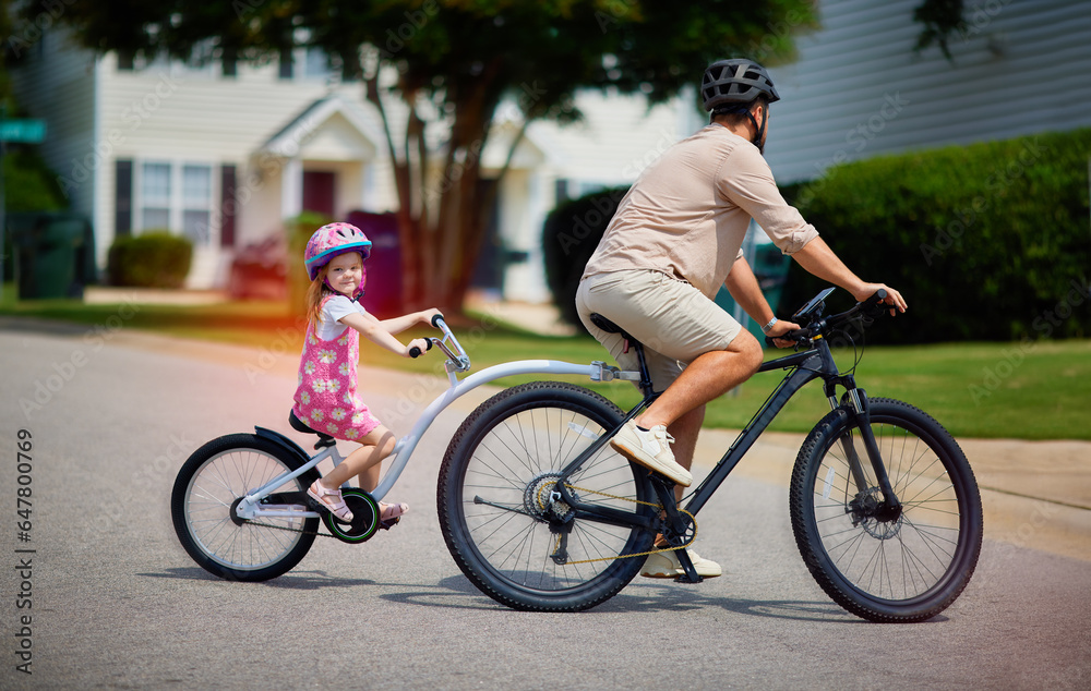 father and daughter, young kid cycling together. bicycle with towable ...