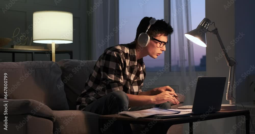 On the sofa, a young Caucasian man in headphones showcases his unique ...