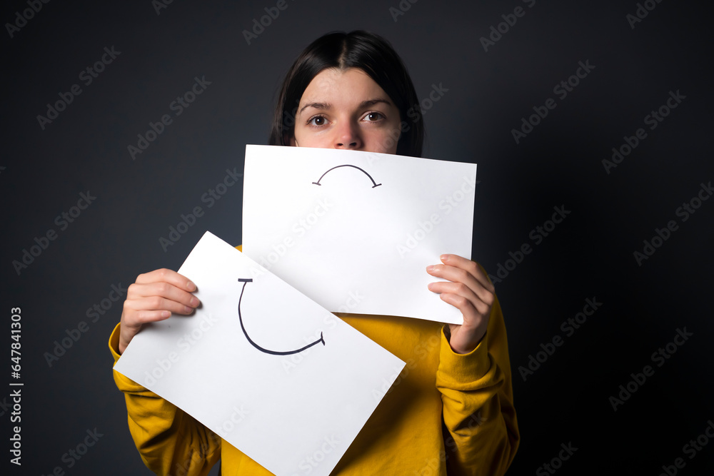 Girl is hiding emotions, holding 2 papers with smile and sadness. Stock ...