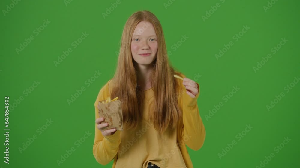 Green screen. Blonde teenage girl smiles and eats french fries. Modern ...