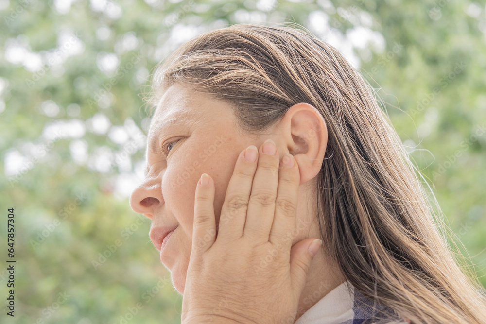 mature caucasian woman 50 years holding hand to sore ear, close up ...