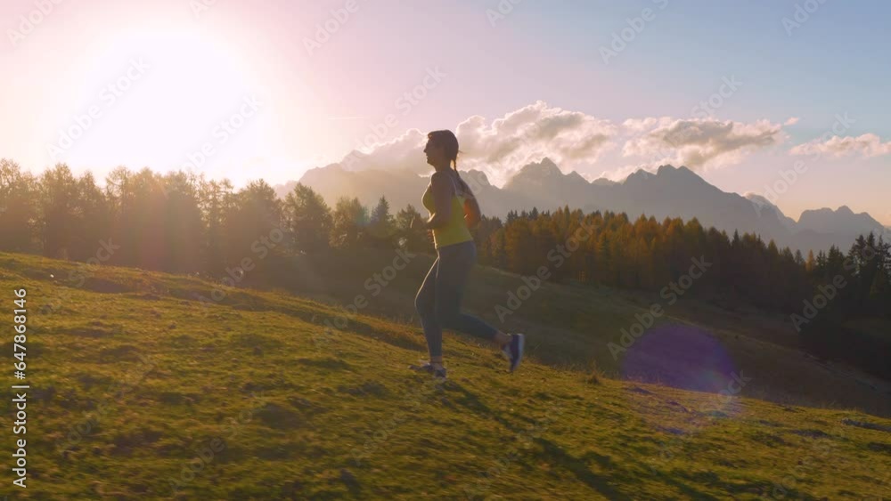 CLOSE UP, LENS FLARE: Fit young lady in sportswear runs on top of a ...