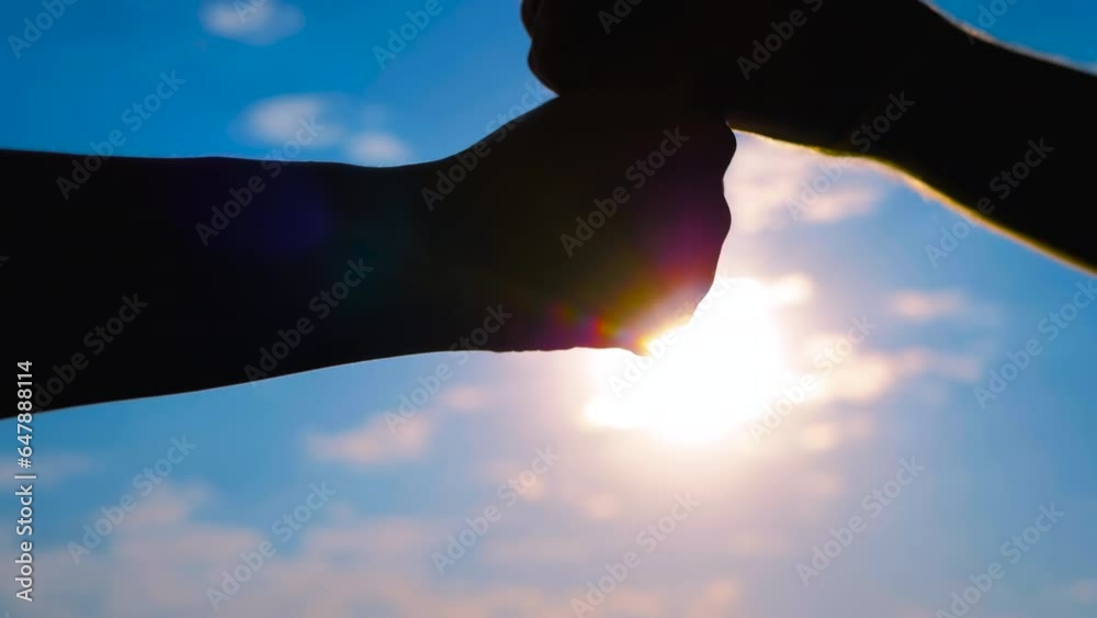 Close up: silhouettes of man and woman hands are bumping fists against ...