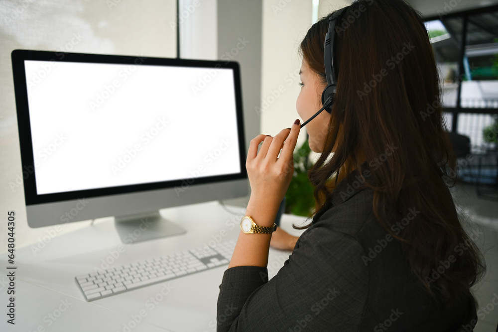 Side view of female telemarketer operator wearing headset and working ...