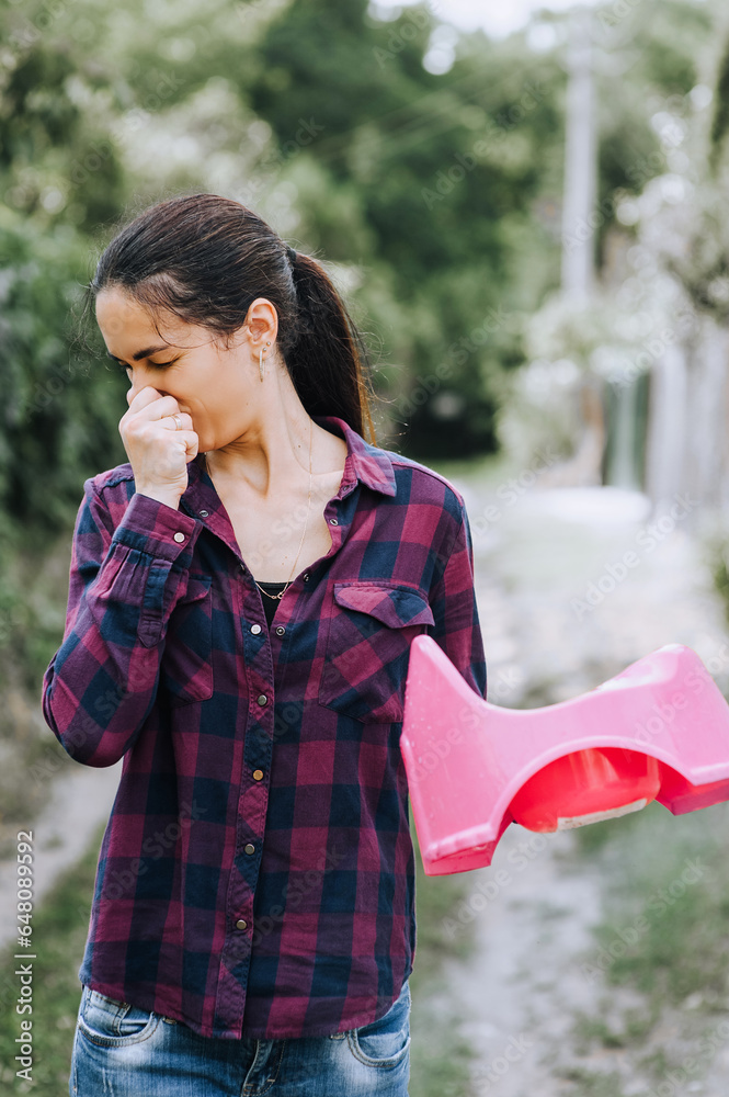 A woman, a girl, a mother is holding a pink potty toilet with smelly ...