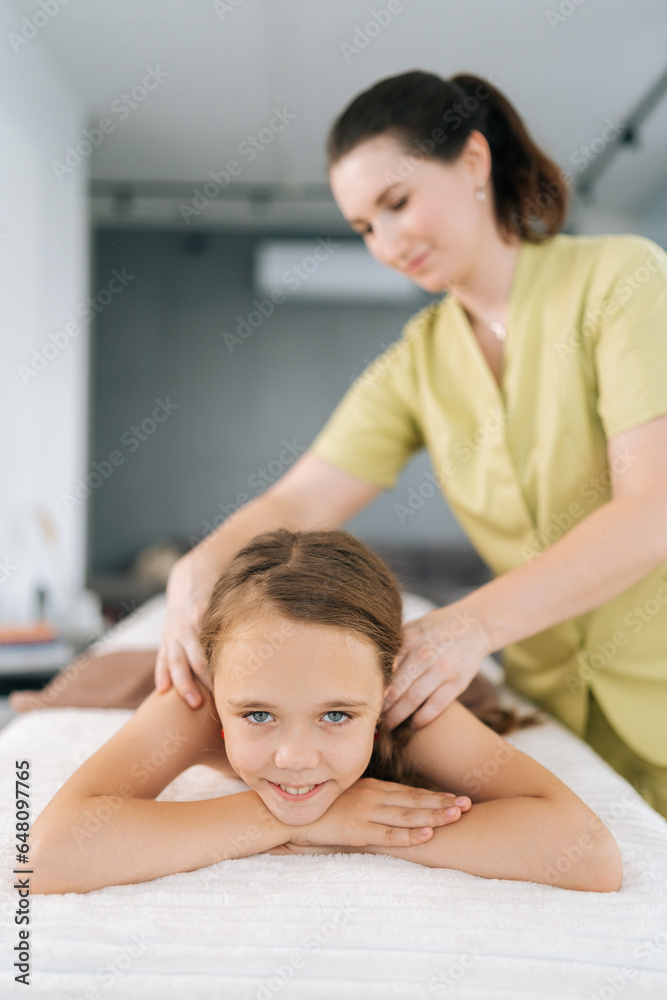 Vertical portrait of happy cute little girl having neck, shoulder and ...