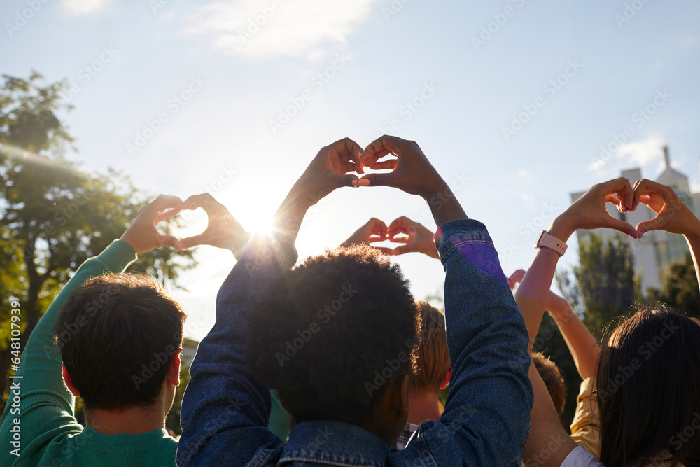 Group friends doing heart symbol shape with both hands against sunset ...