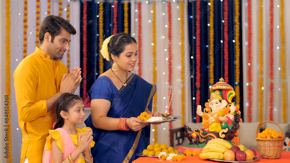 Beautiful Indian family worshipping Lord Ganesha with pooja ki thali ...