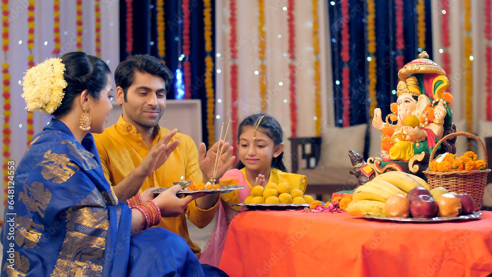 Loving Indian family worshipping Lord Ganesha with pooja ki thali a ...