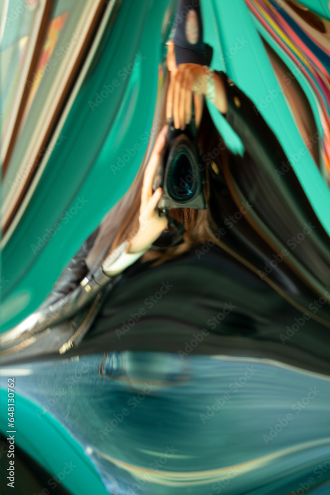 Girl photographer with a camera, distorted in a distorted mirror, a ...