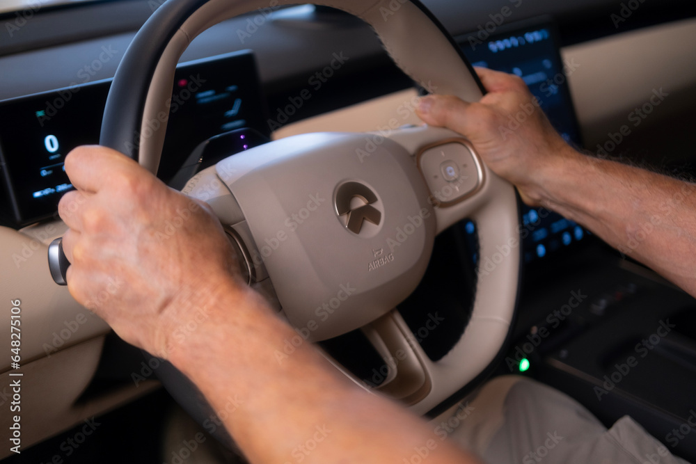 Behind steering wheel of Nio electric car, male hands on Driver's ...
