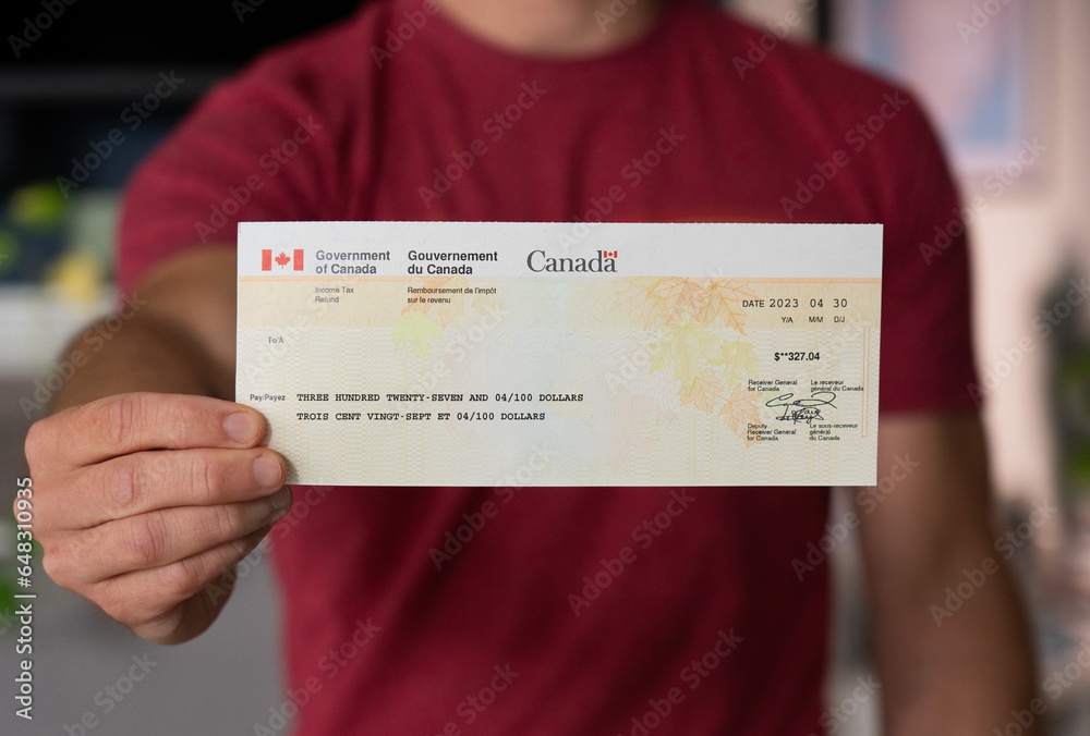 Man Holding a Canada Tax Refund Cheque Stock Photo | Adobe Stock