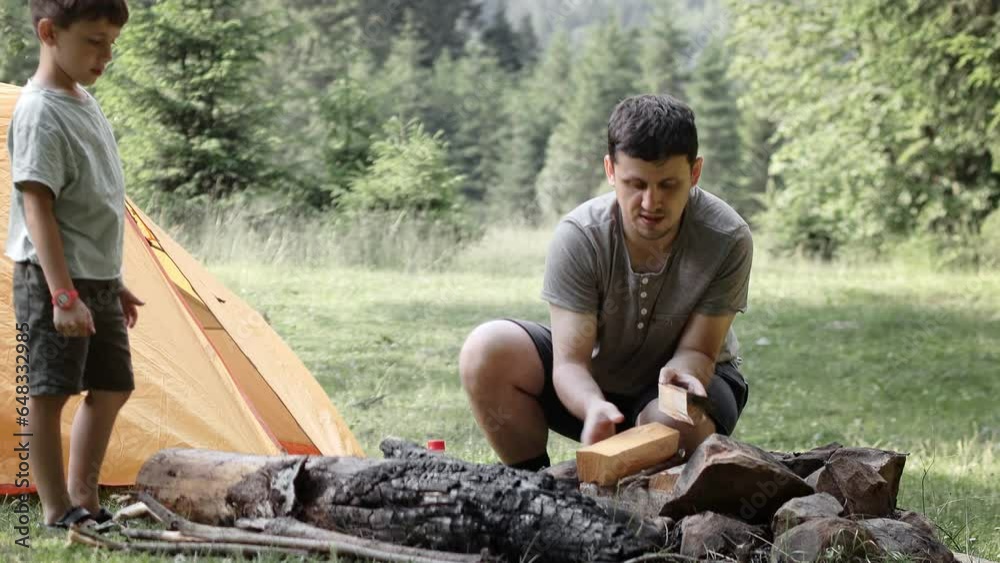 Young scout showing his son how to make campfire during trip in natural ...