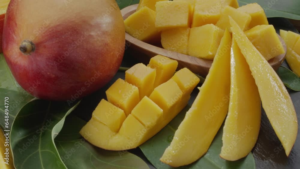 Ripe mango fruits with slices and mango leaves slowly move in the frame ...