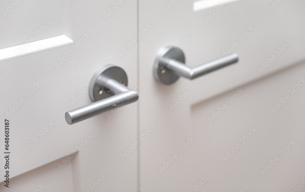 silver metal door handle against a dark wood door. The handle's curved ...