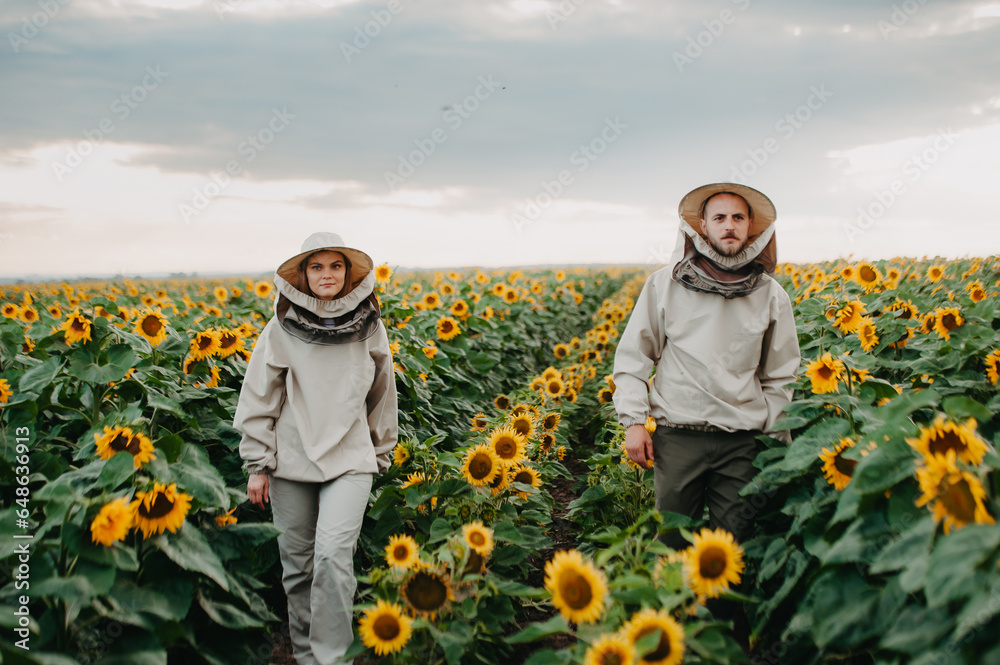 Young beekeepers work with bees in the apiary and eat honey.A young ...